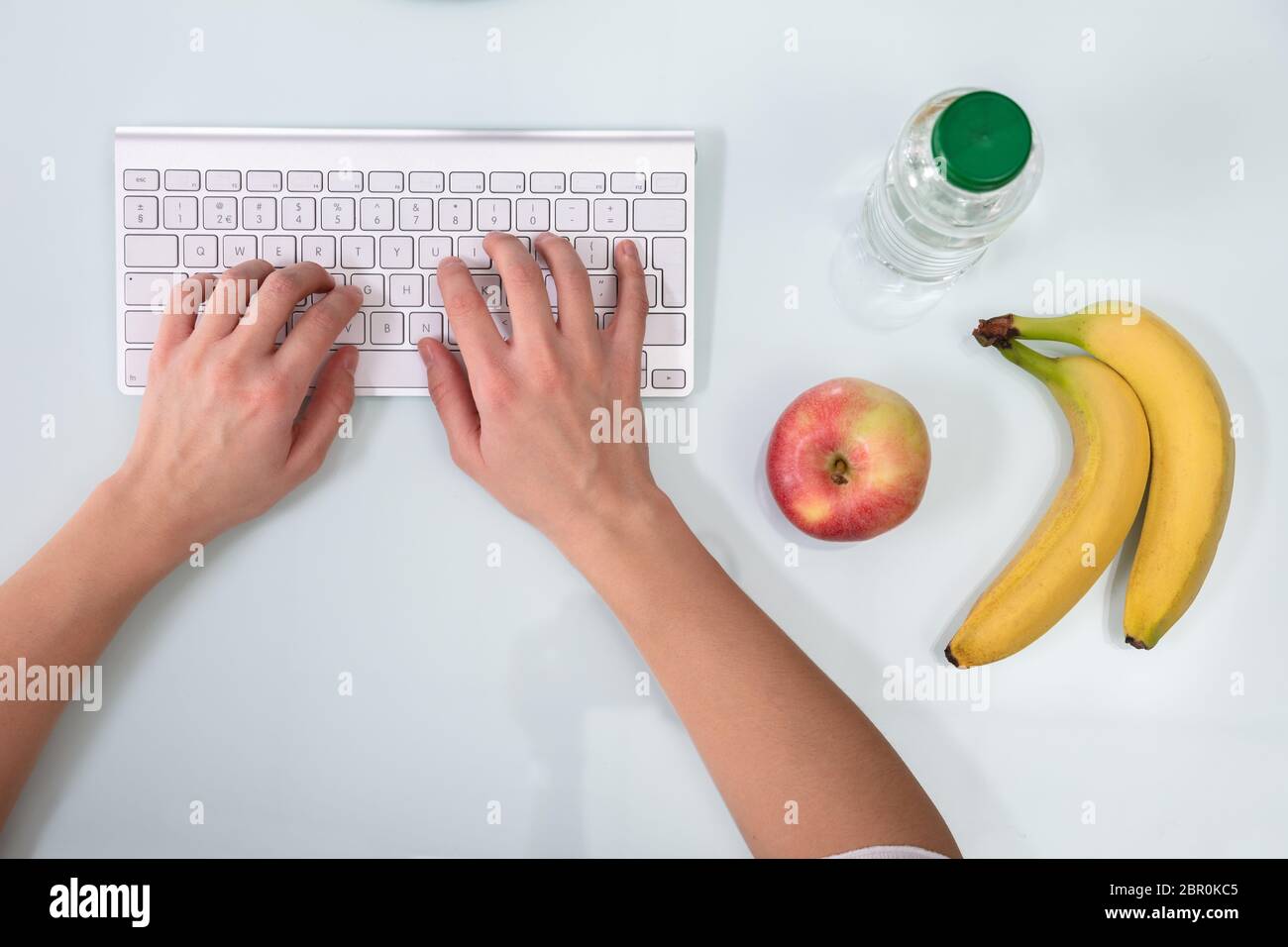 An Elevated View Of Businessperson's Hand Working On Computer Keyboard With Fresh Fruits On Desk ...