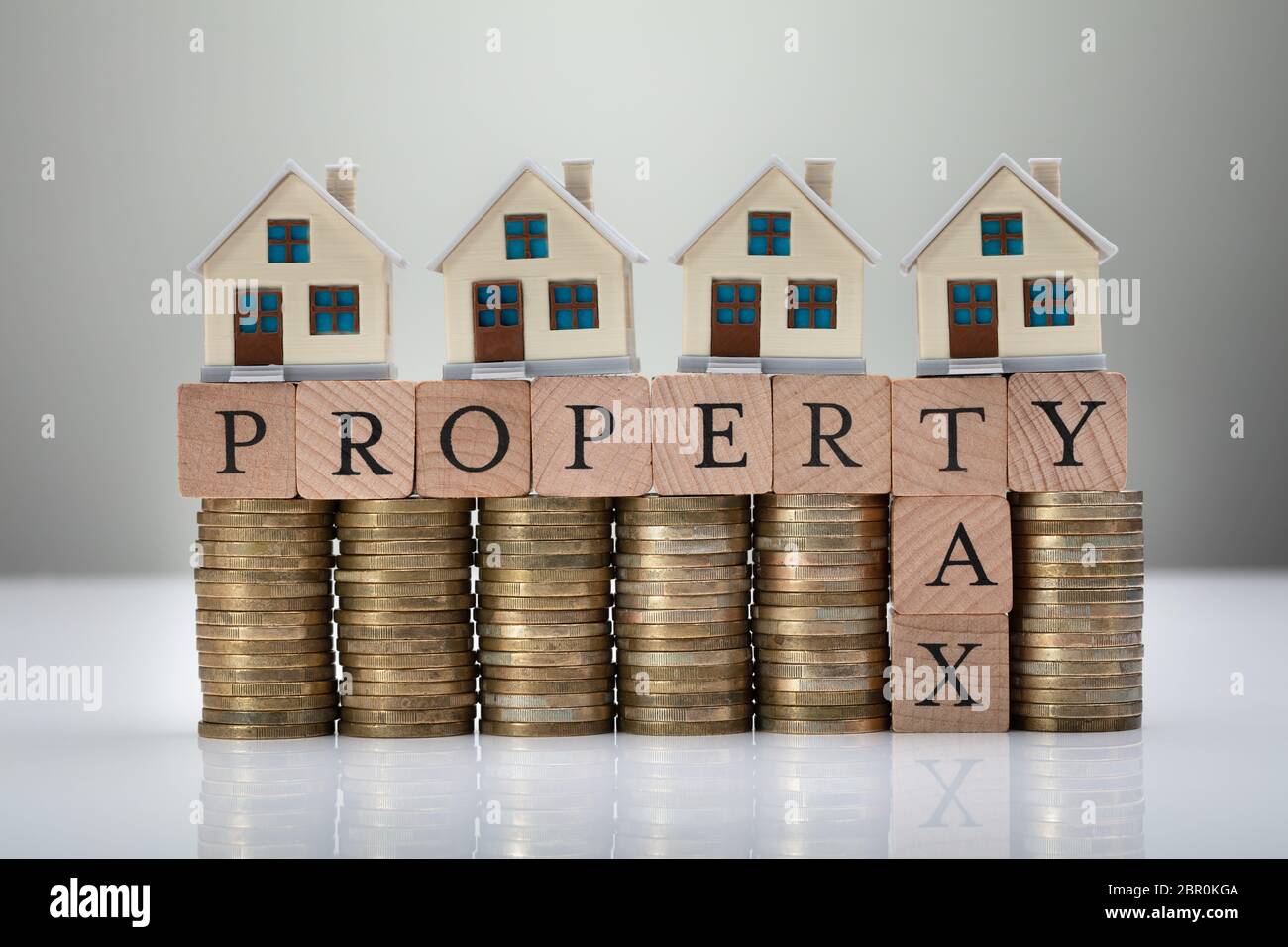 House Models On Stacked Coins Showing Property Tax Concept On White ...
