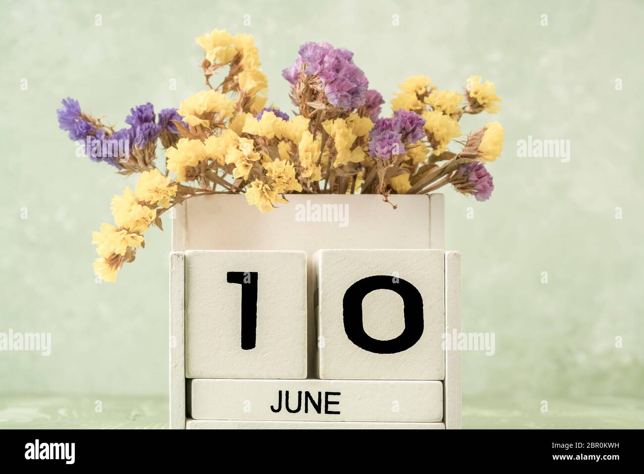 White cube calendar for june decorated with flowers over green ...