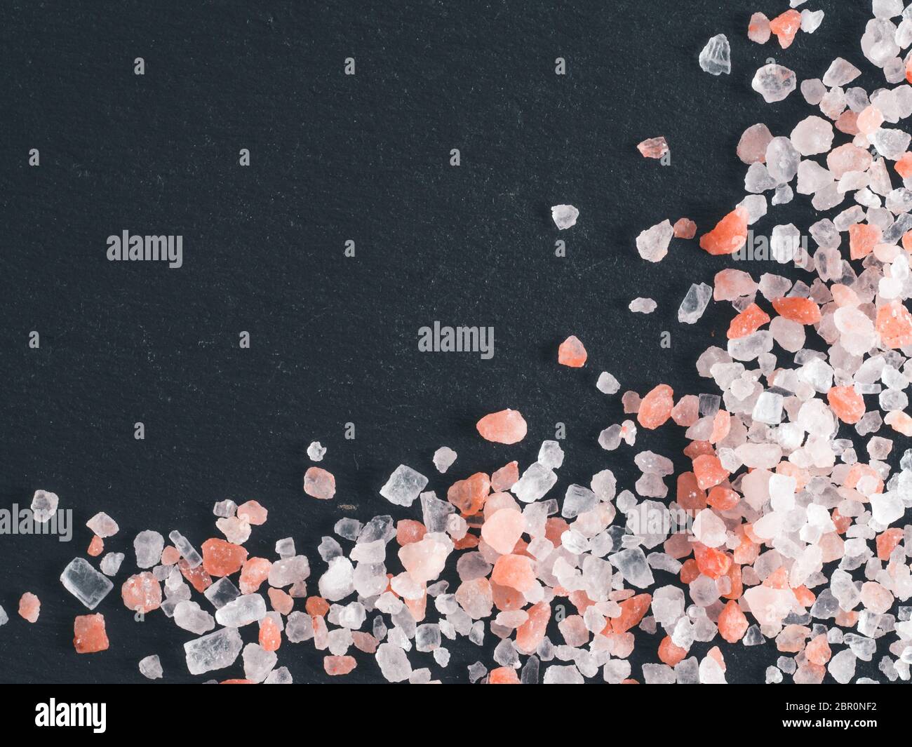 Himalayan pink salt in crystals on black stone background. Copy space ...