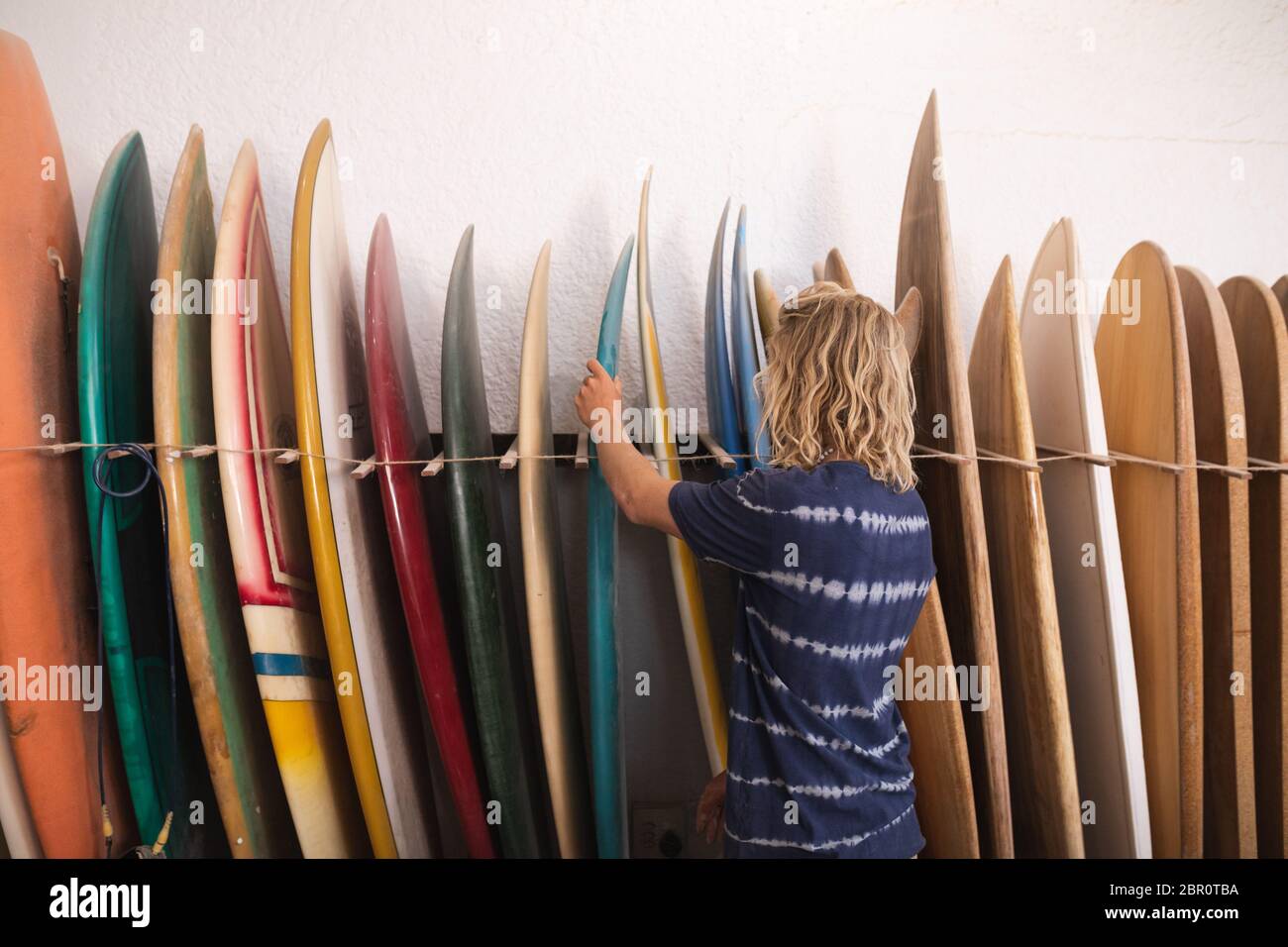 Caucasian male surfboard maker in his studio checking one of the ...