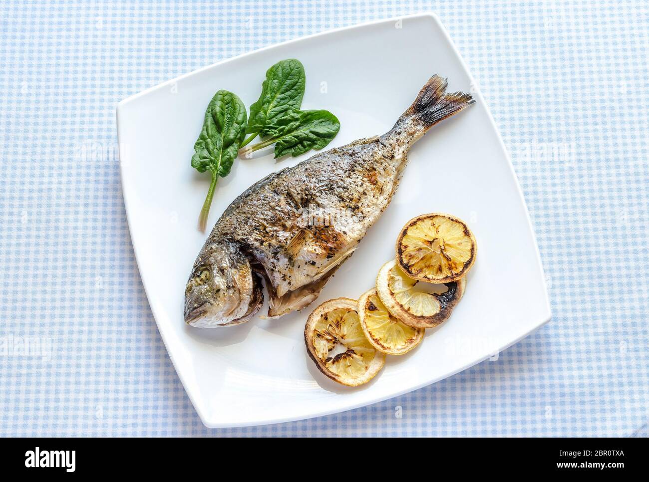 Grilled dorada fish with lemon and spinach Stock Photo - Alamy