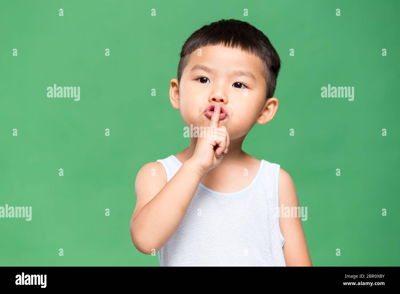 Little kid putting a finger on his lips Stock Photo - Alamy