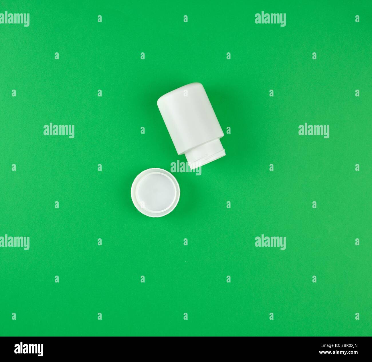 white plastic container for tablets, near the cover, green background ...