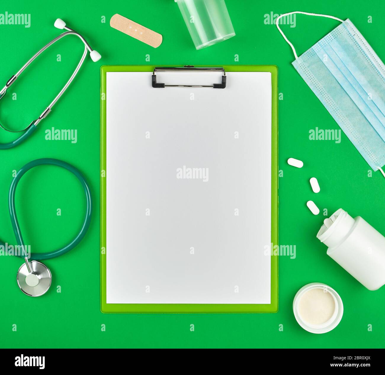 paper holder with empty white sheets, medical stethoscope, pills and ...