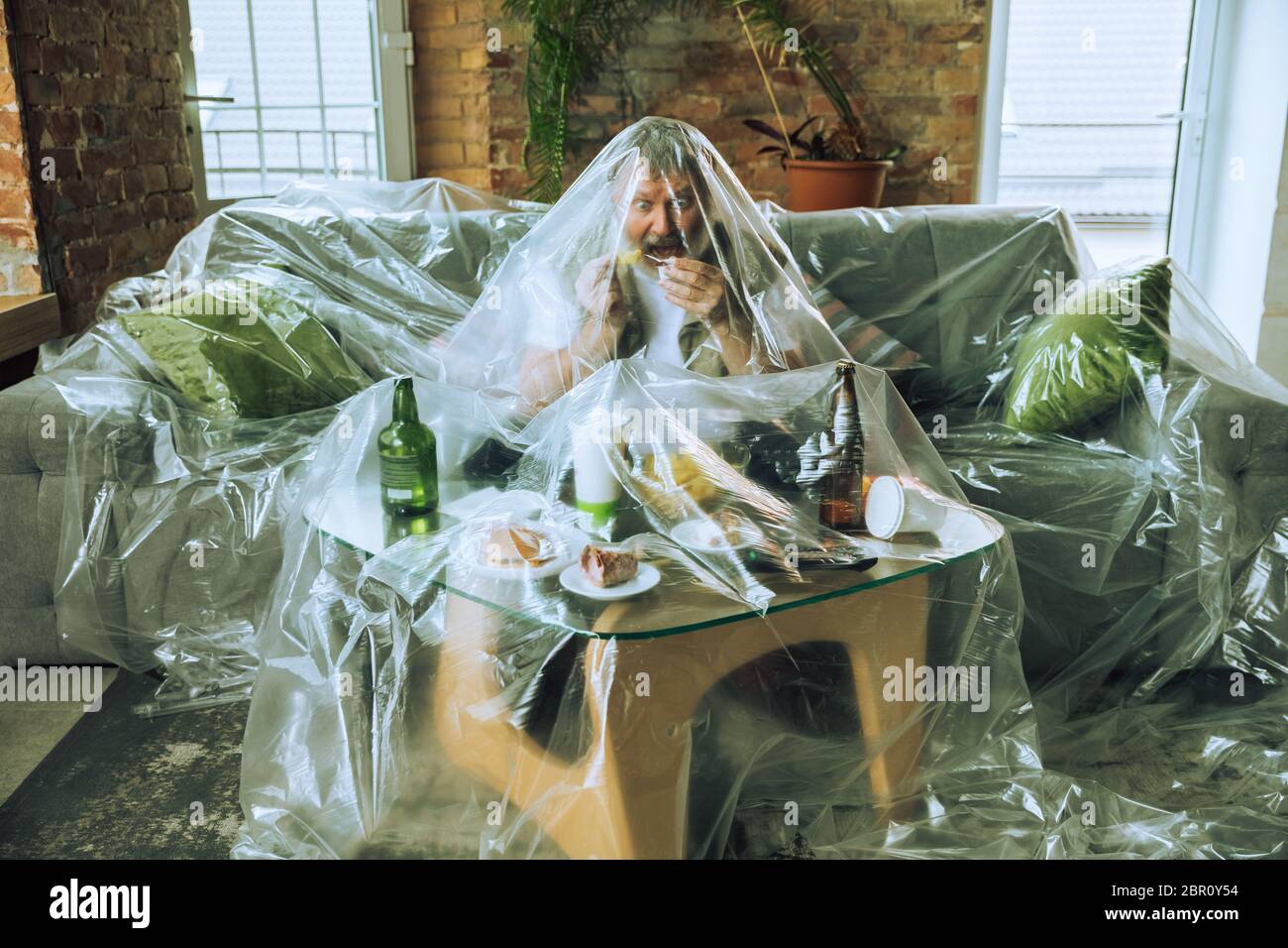 Senior man covered with plastic, eating fast food - environmental ...