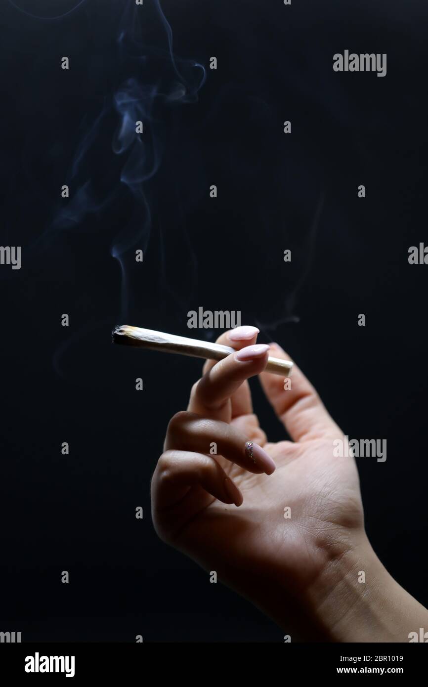 Woman hand holding cigarette. Smoking cannabis joint. Medical use ...