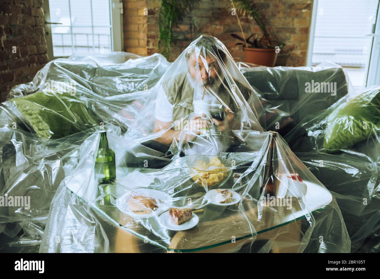 Senior man covered with plastic, eating fast food - environmental ...