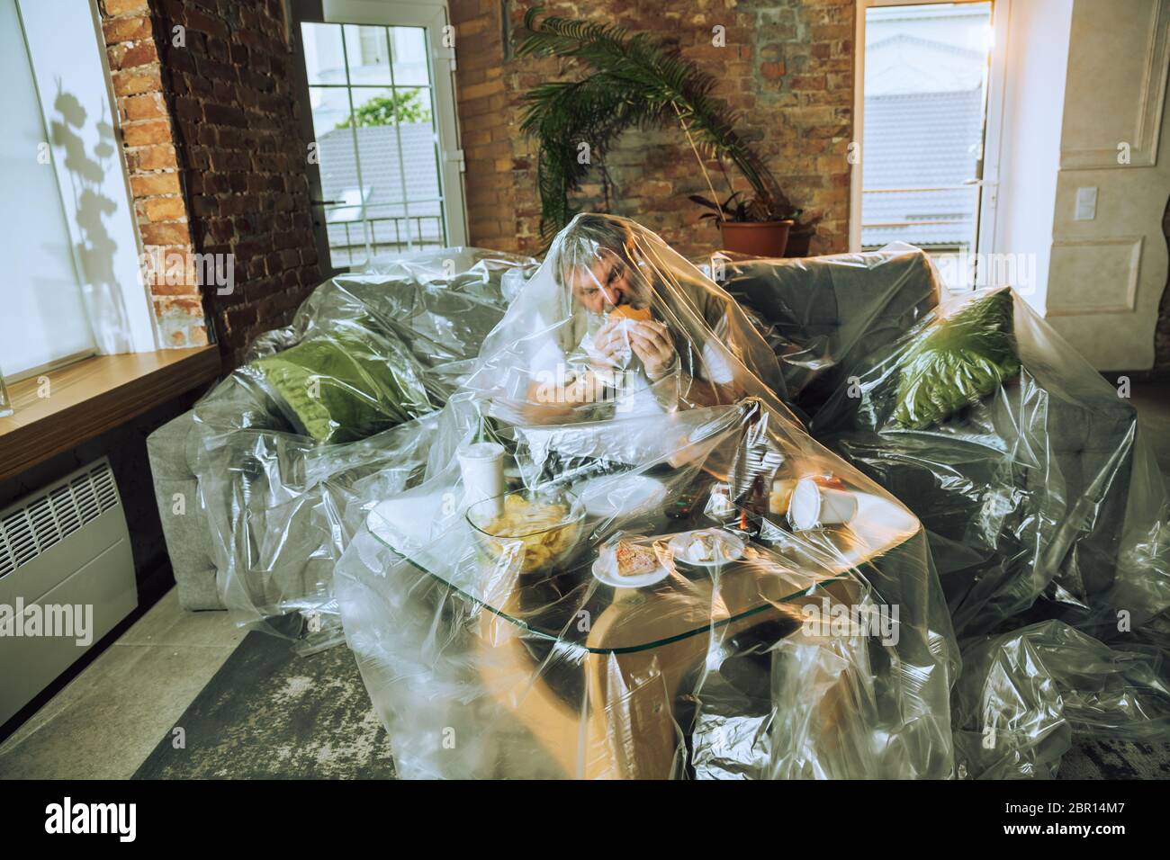 Senior man covered with plastic, eating fast food - environmental ...