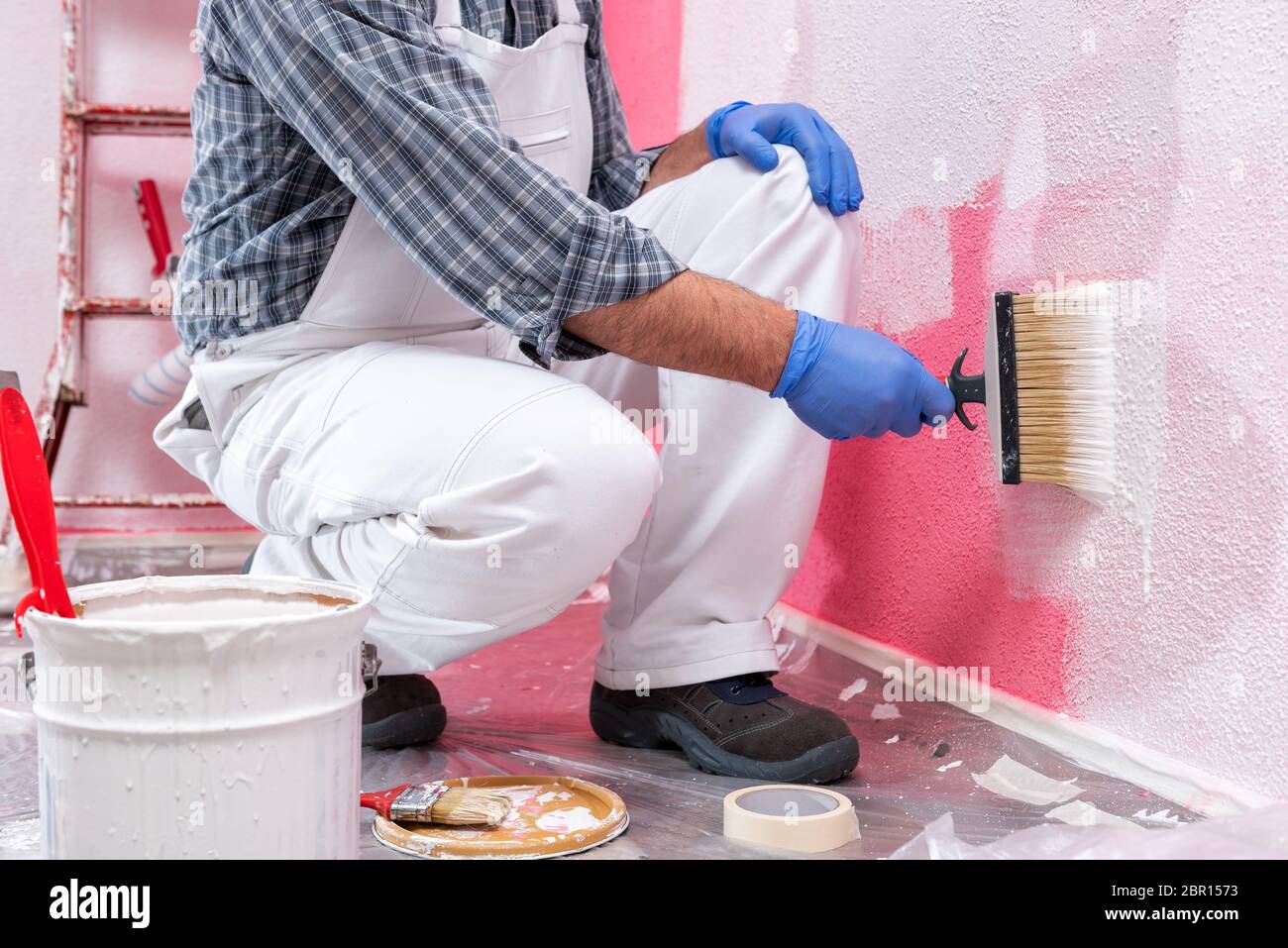 Caucasian house painter worker in white overalls, with the brush ...