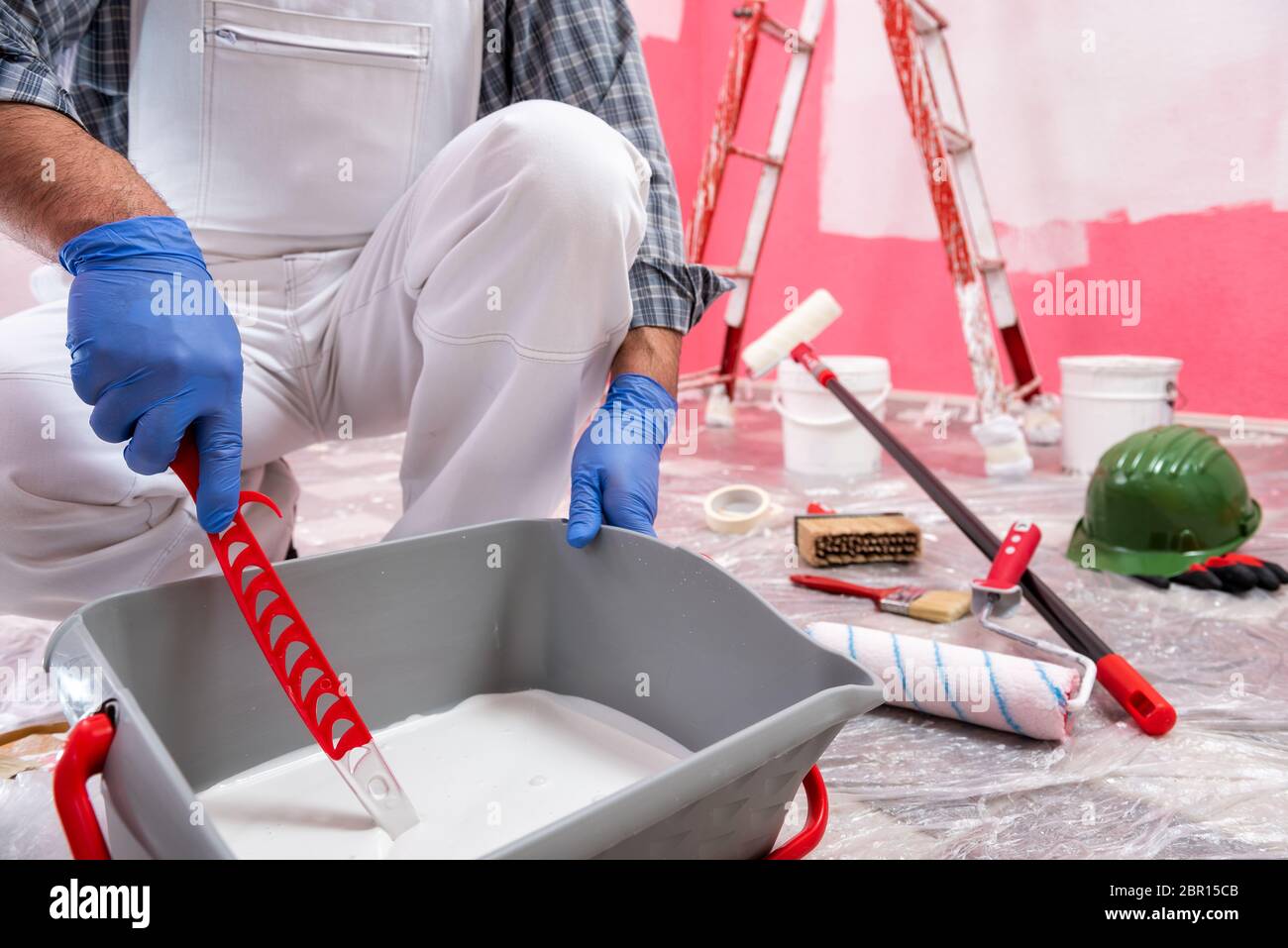 Caucasian house painter worker in white overalls, prepare the white ...