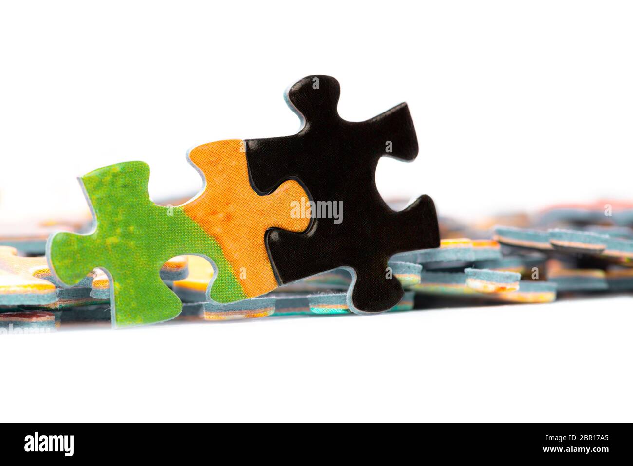 Two bright puzzle pieces connected in front of separated pieces. White ...