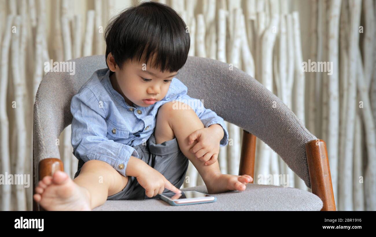 Little boy looking at cellphone Stock Photo - Alamy