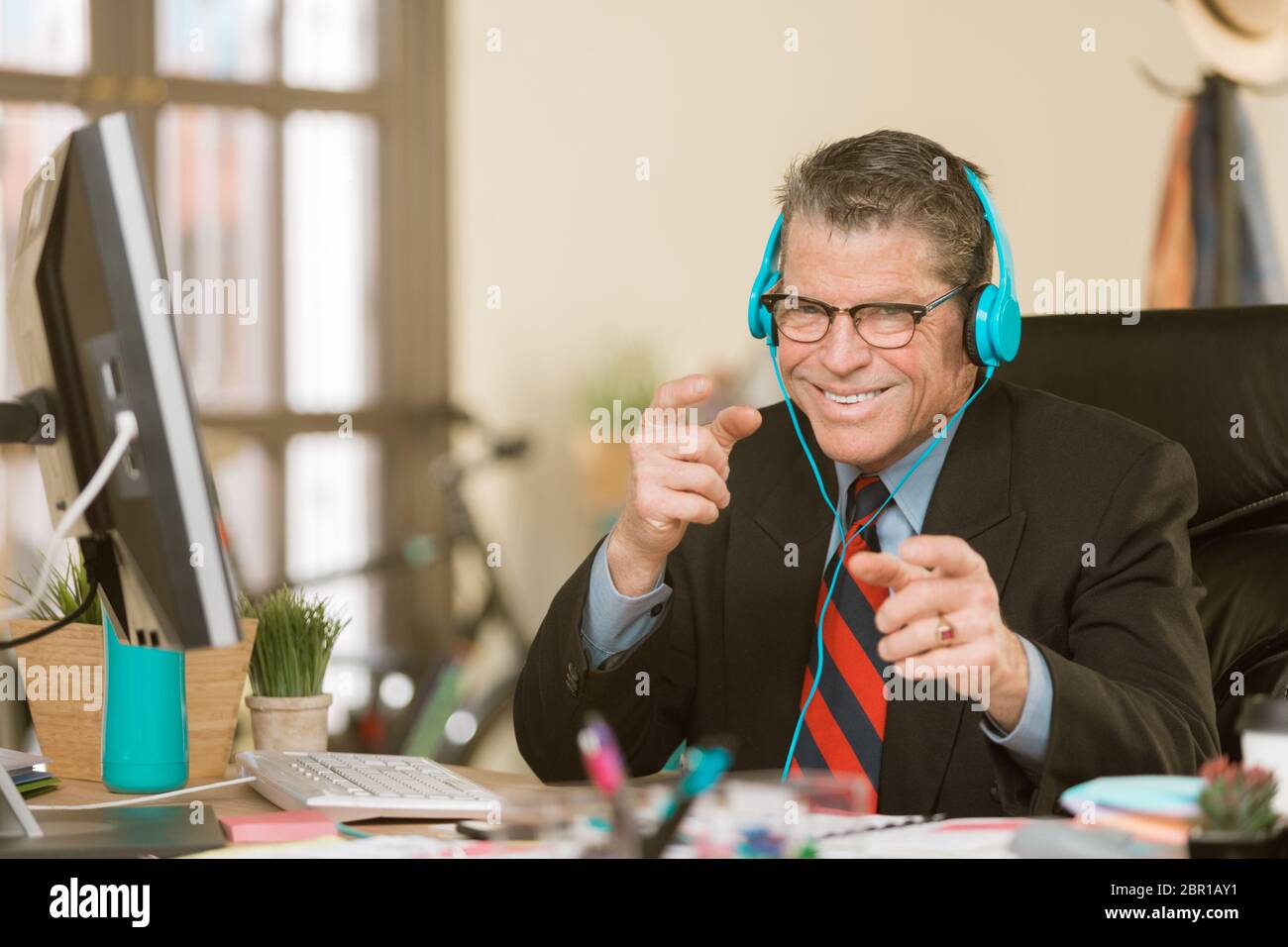 Professional man in a creative office listening to headphones and ...