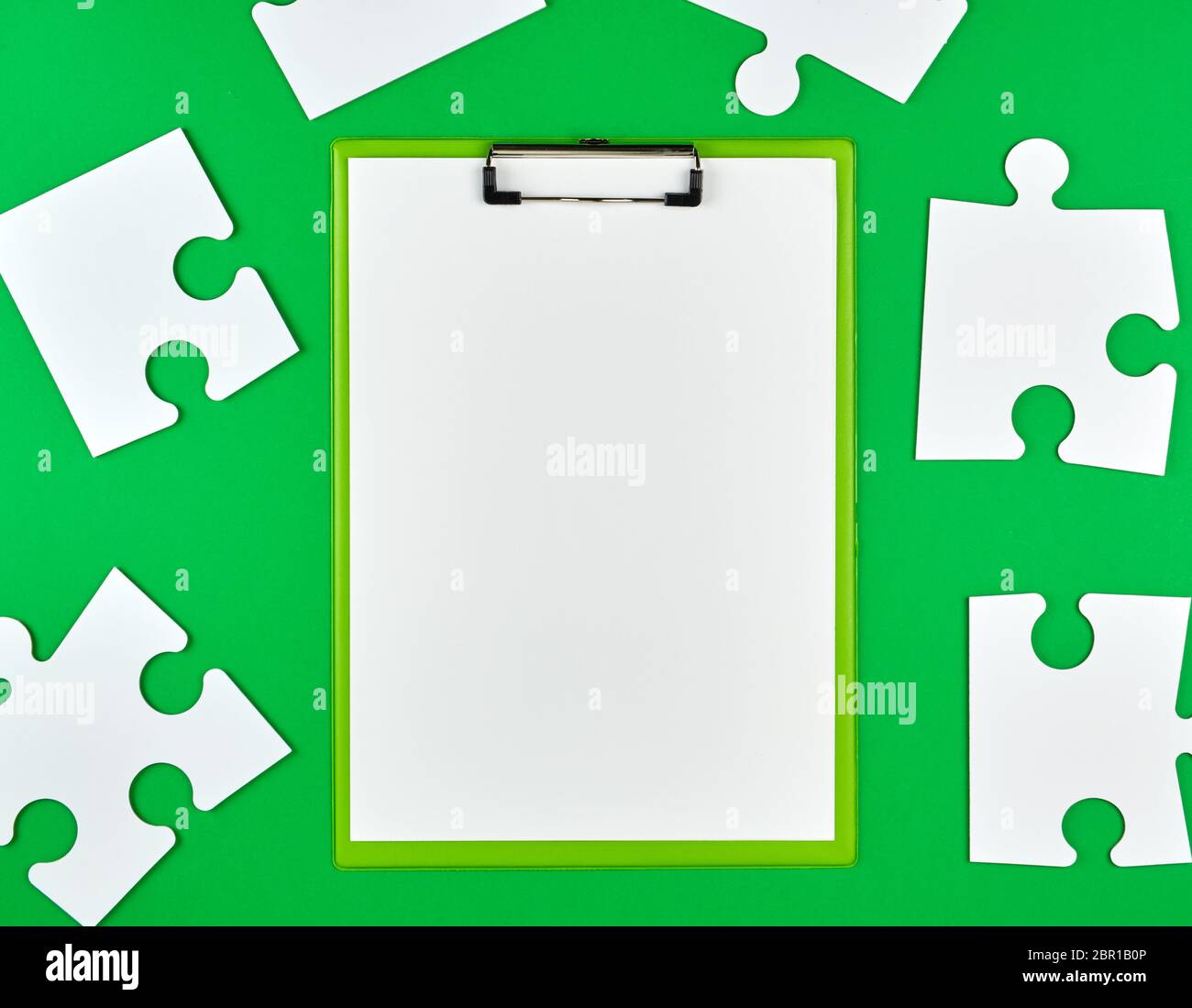 paper clip and white large paper puzzles on a green background, top ...