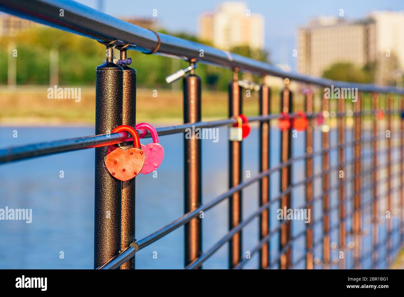 Colorful metal locks hanging on black railings in the sunrise light ...