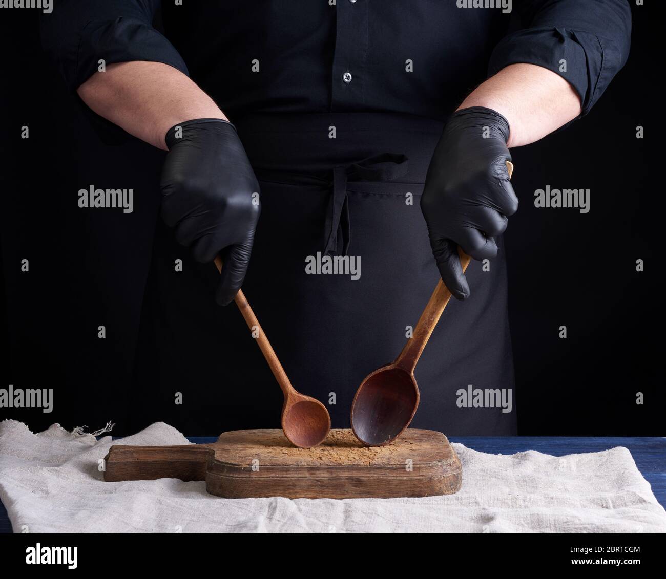 chef in black latex gloves and a black uniform holds wooden vintage ...