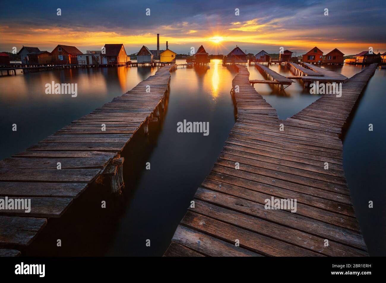 Sunset over lake Bokod with wooden pier and floating houses, power ...