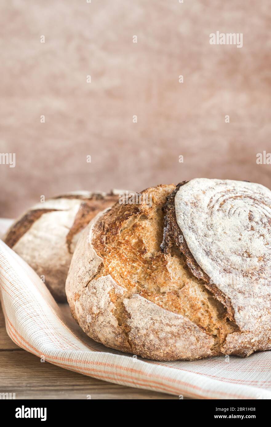 Two loaves of bread on the old-fashioned background Stock Photo - Alamy