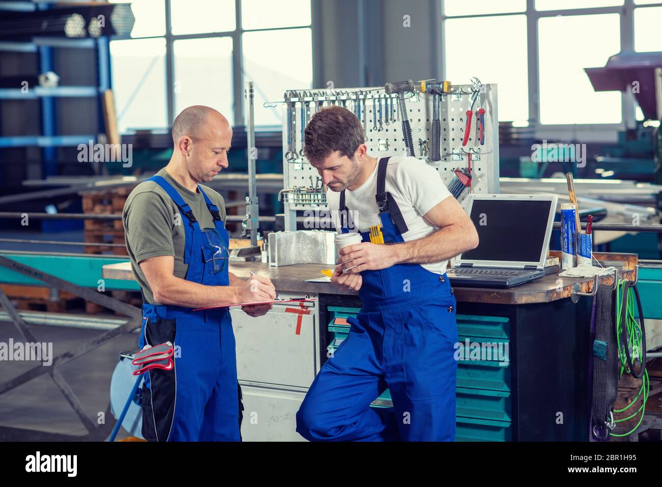two worker in factory on work bench in conversation Stock Photo - Alamy