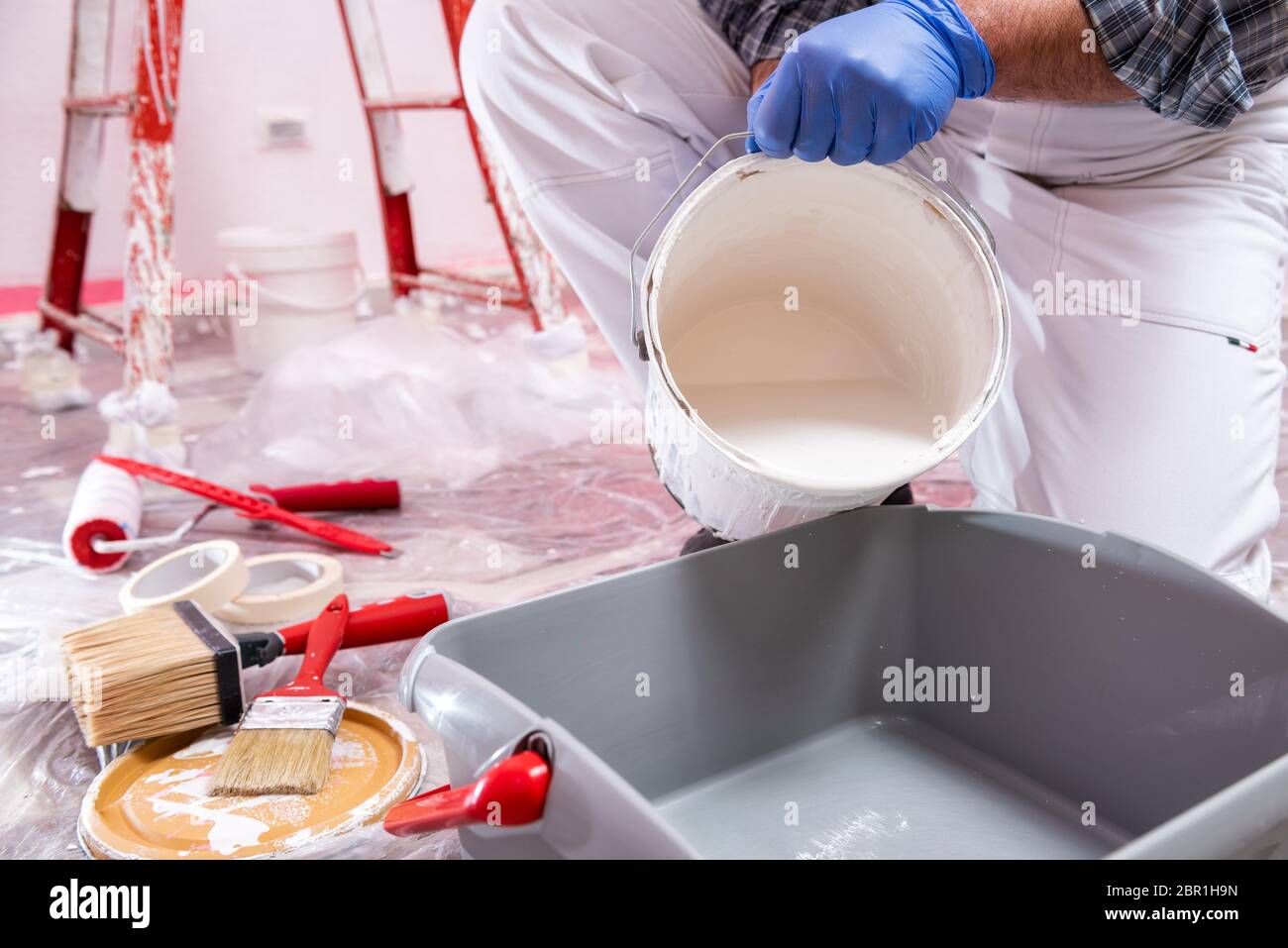 Caucasian house painter worker in white overalls, prepare the white ...