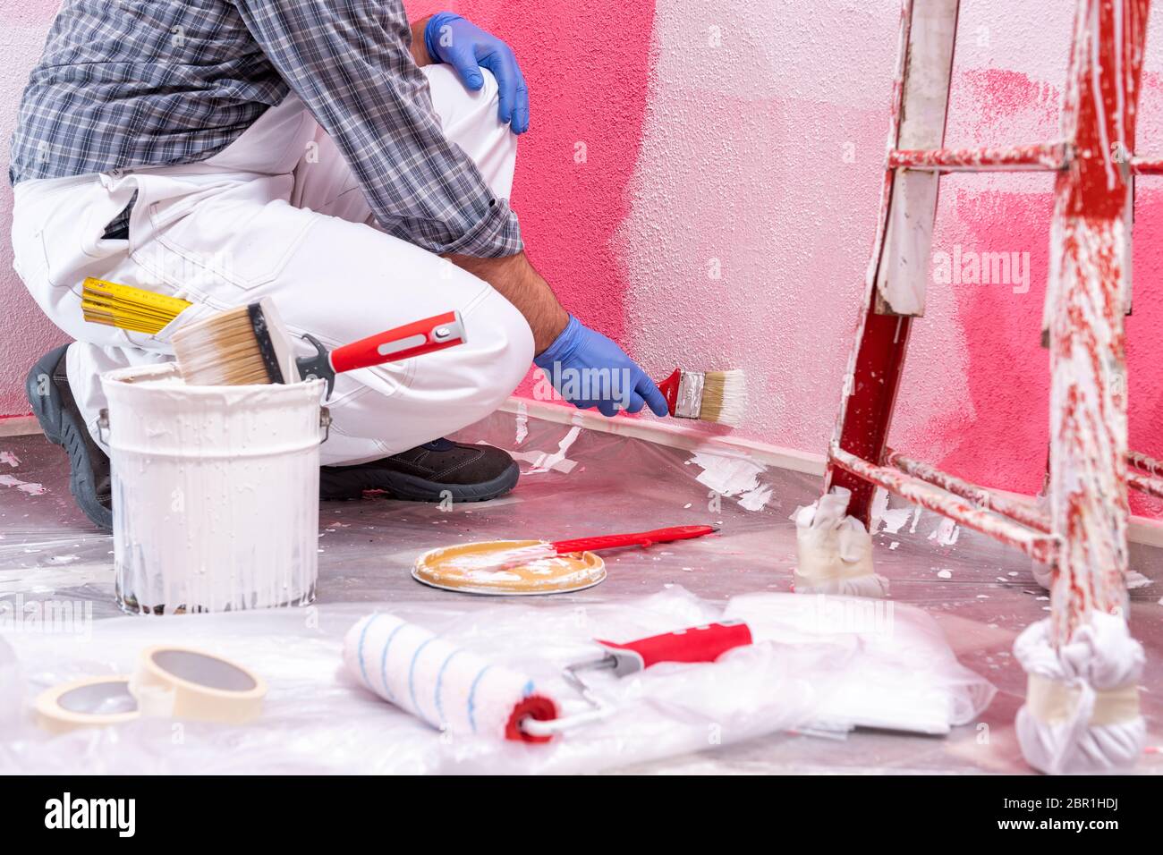 Caucasian house painter worker in white overalls, painting the pink ...