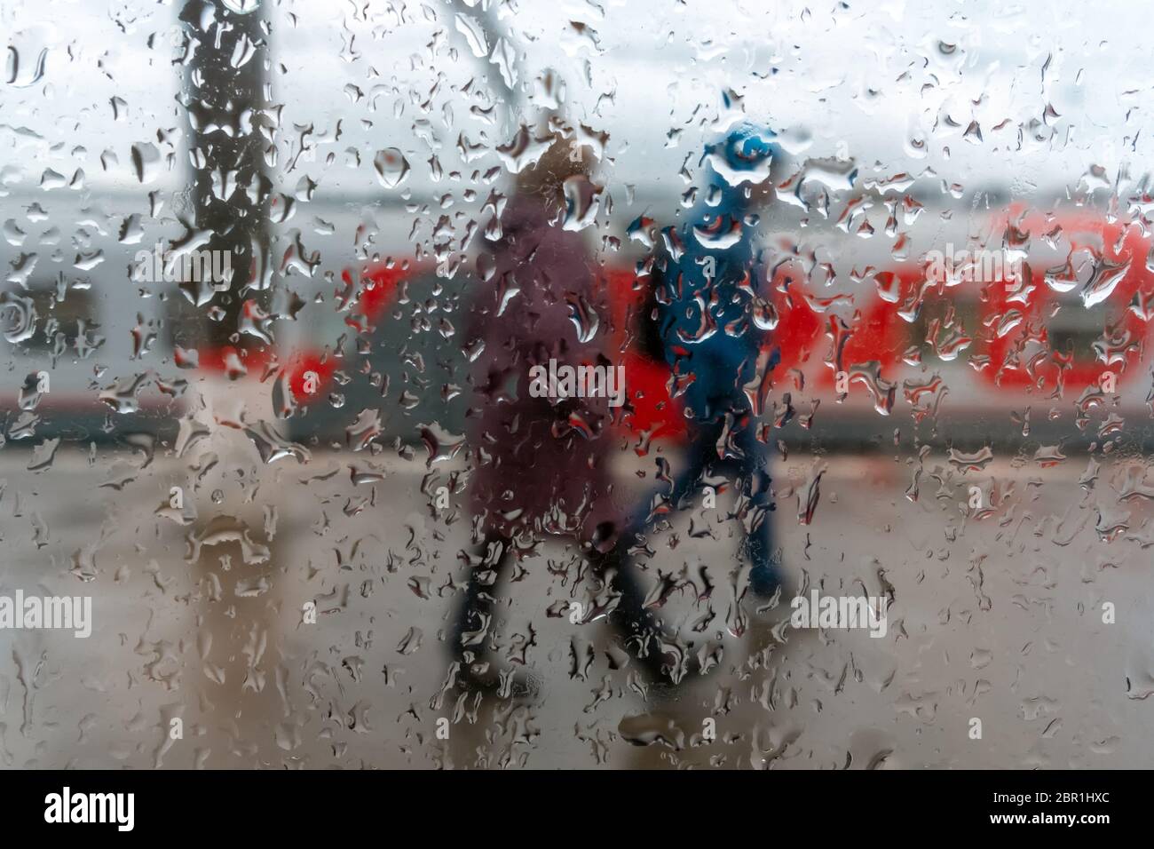 Passengers are walking on railway station. View through the glass with ...
