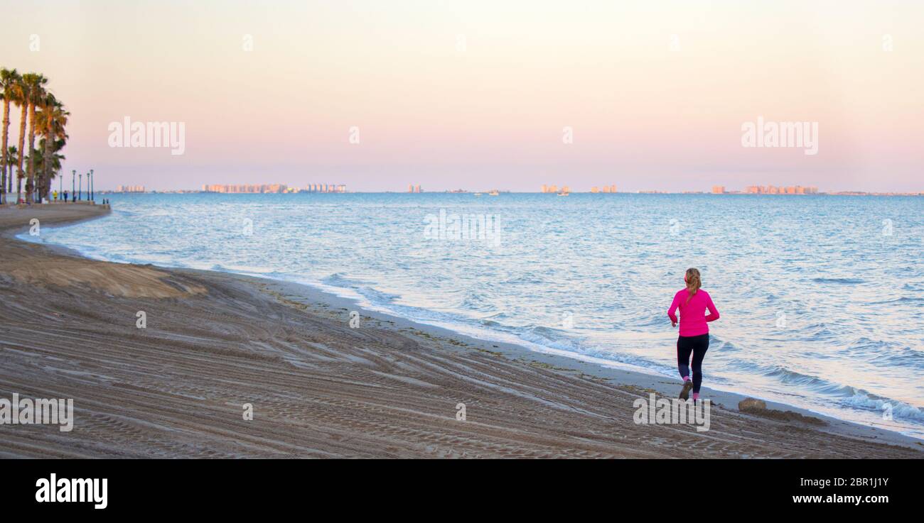 Senior sportswoman running at the beach in Spanish coasts. Athletic old ...