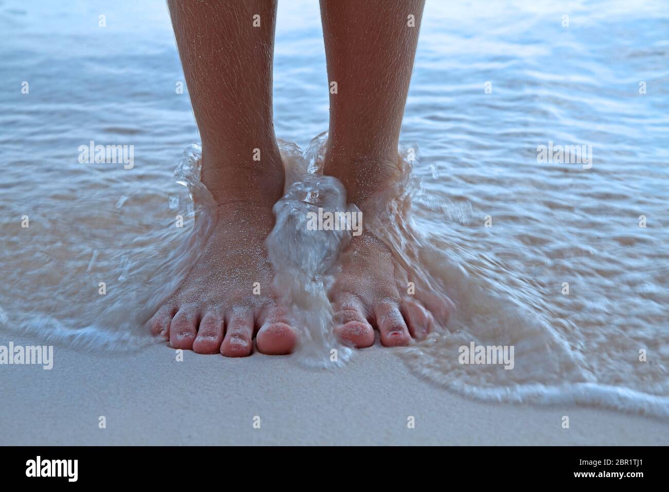 A close up of feet, on the sand, with surf breaking around them Stock ...