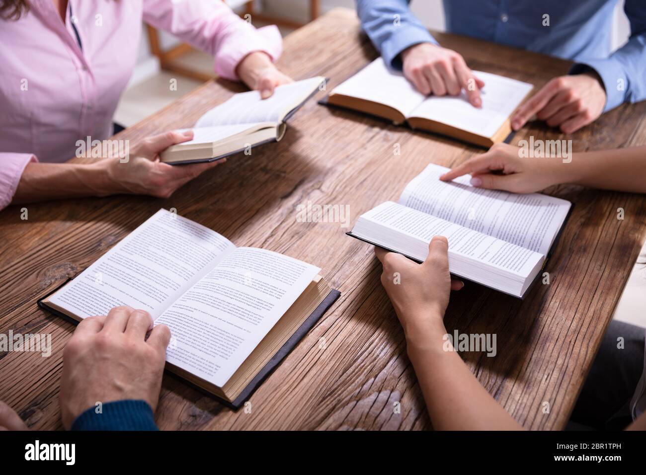Group Of People Reading Bible On Wooden Desk Stock Photo - Alamy