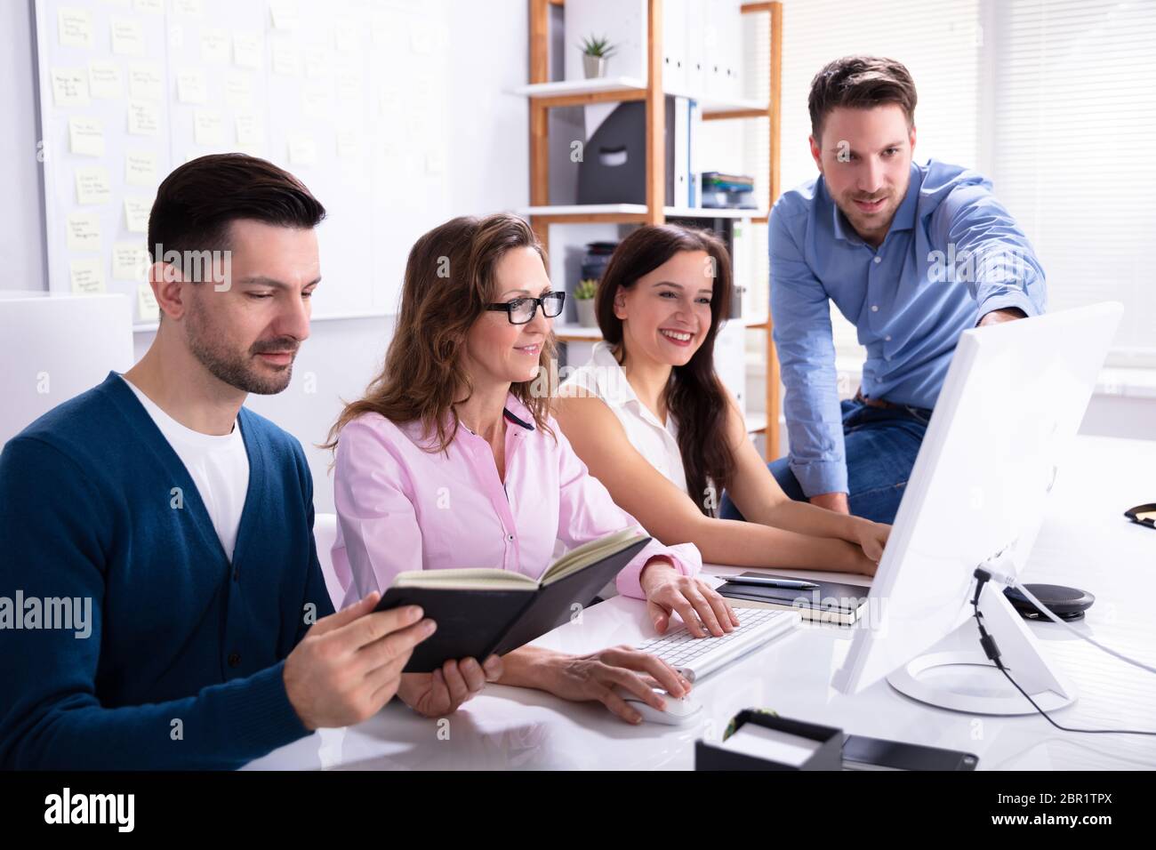 Young Businessman Explaining Plan To Colleagues On Compute At Workplace ...