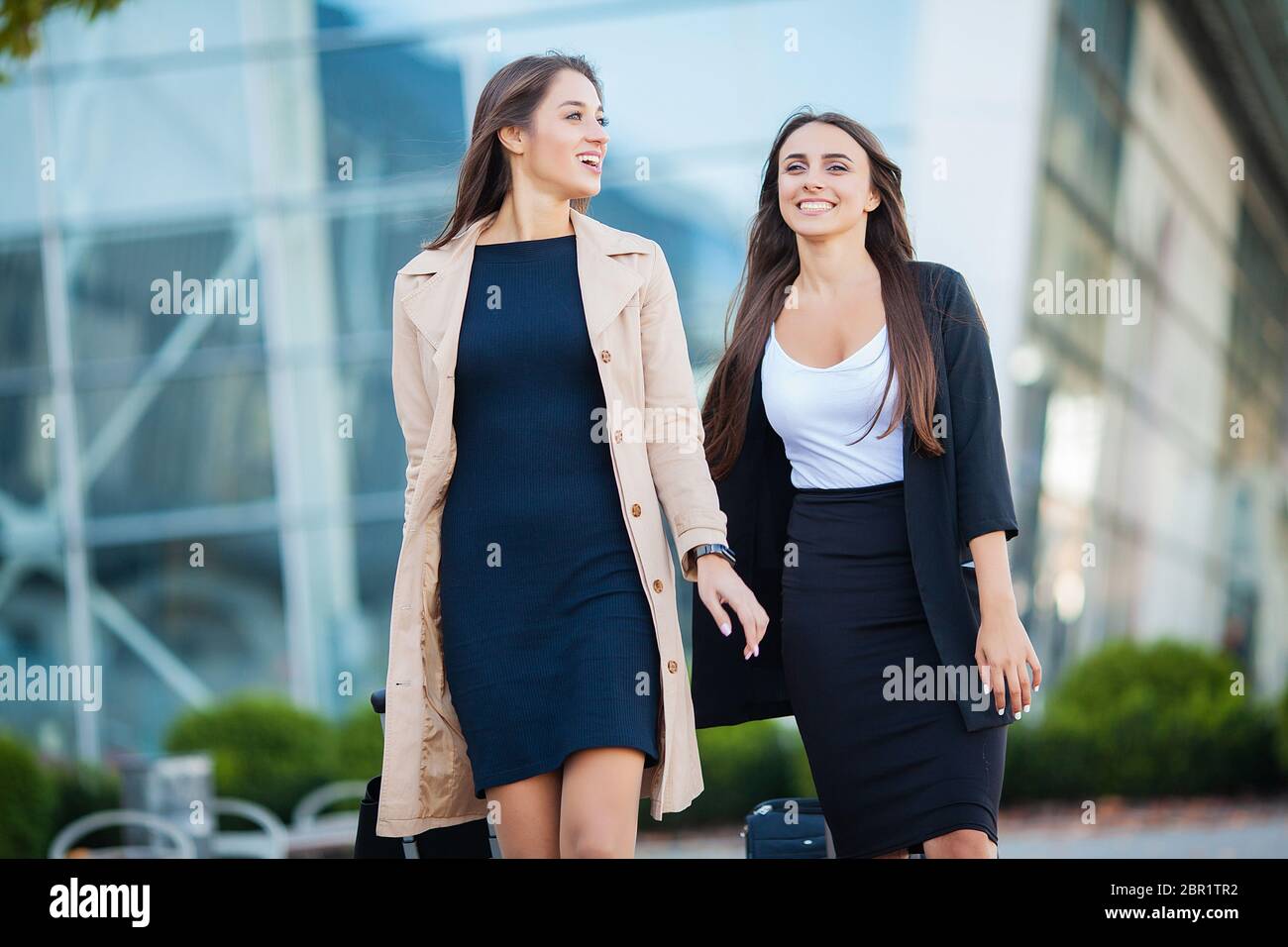 Vacation. Two happy girls traveling abroad together, carrying suitcase ...