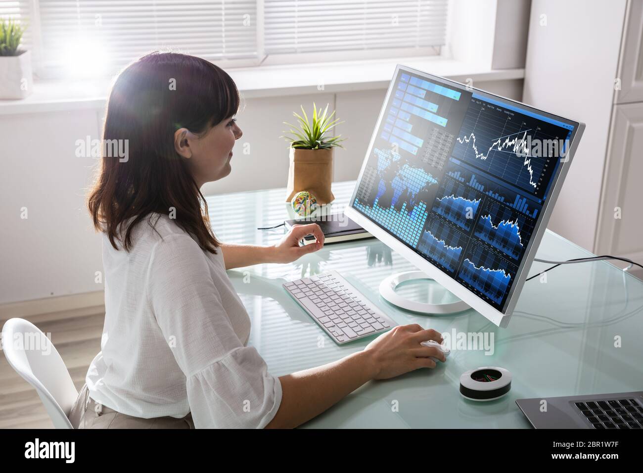 Young Female Stock Market Broker Analyzing Graph On Computer At ...