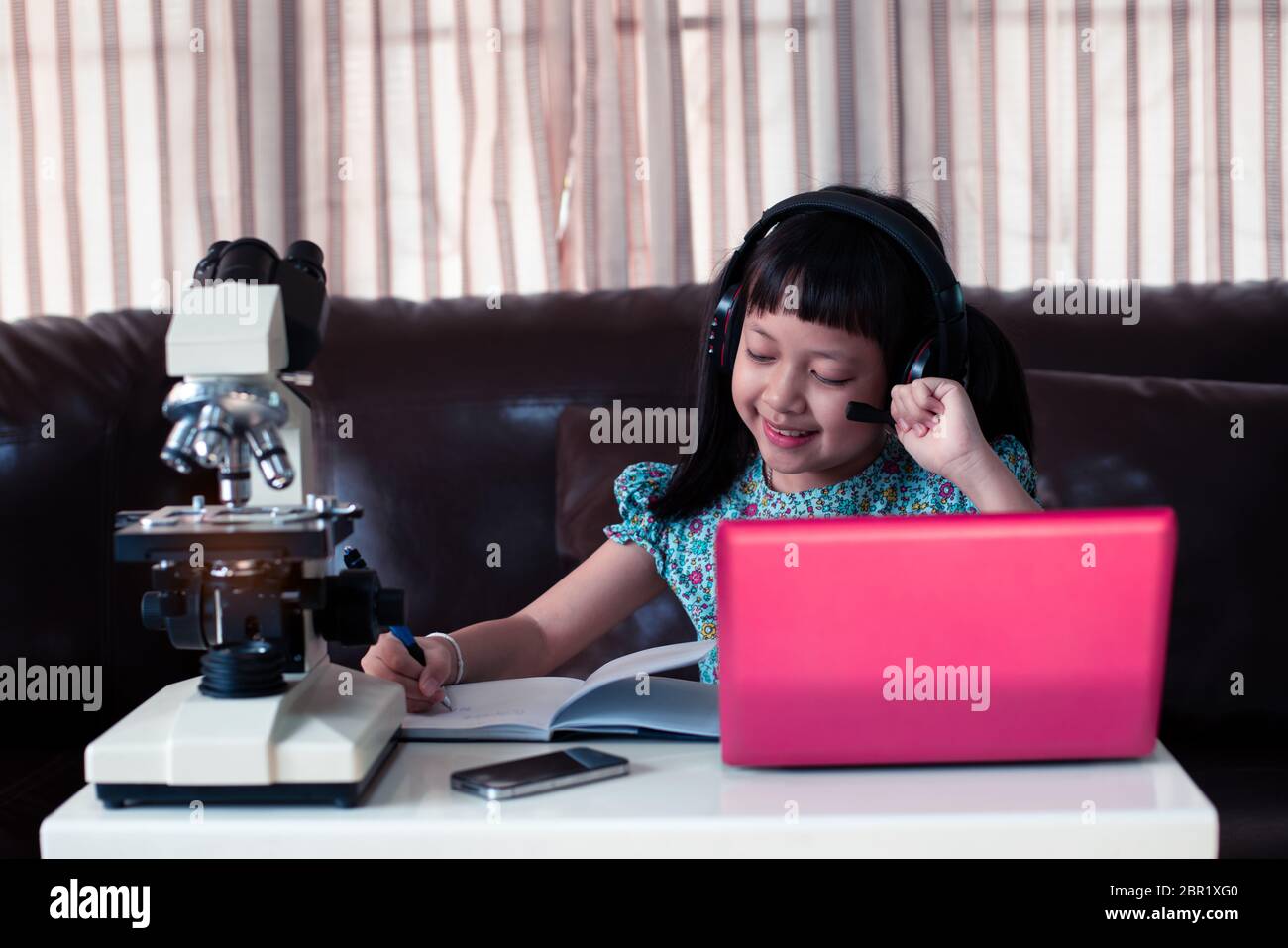 Asian little child girl wearing headphones learning online by using ...