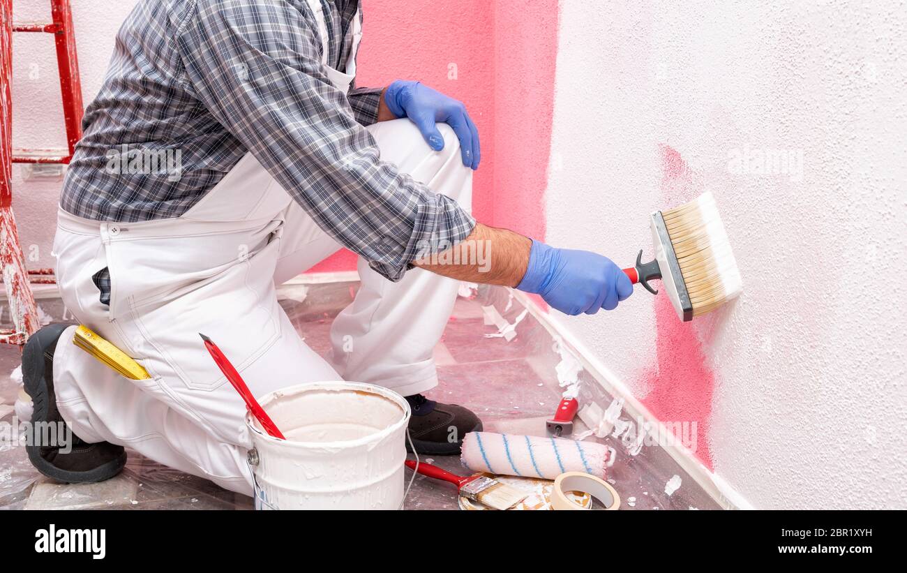 Caucasian house painter worker in white overalls, with the brush ...