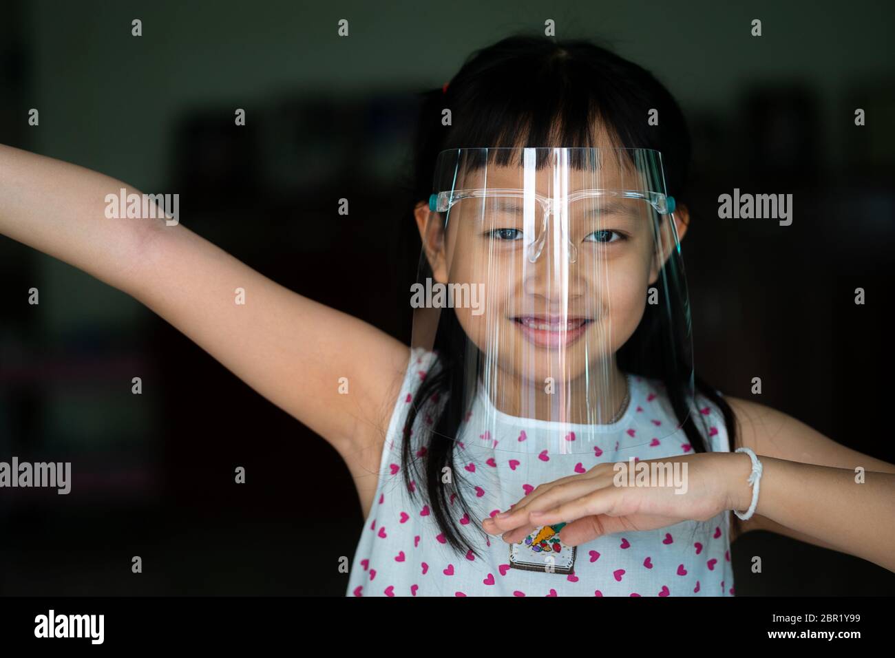 Happy little child girl with a plastic face shield for a virus ...