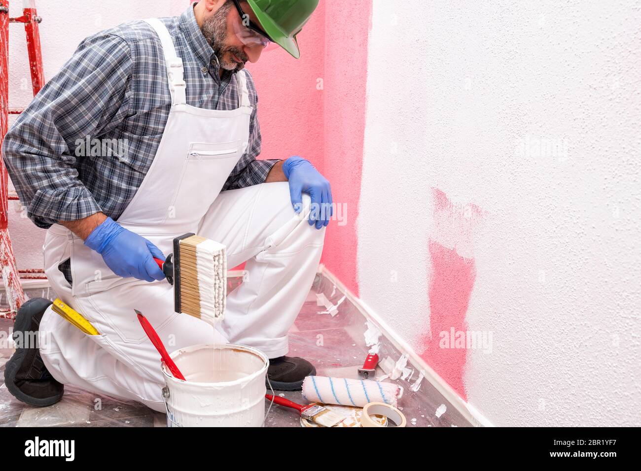 Caucasian house painter worker in white overalls, with helmet and ...