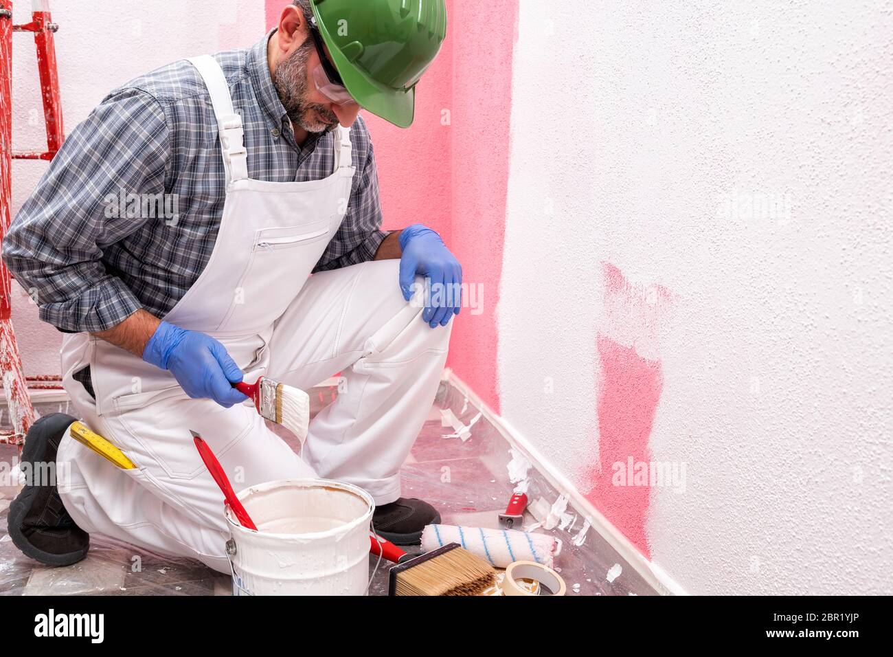 Caucasian house painter worker in white overalls, with helmet and ...