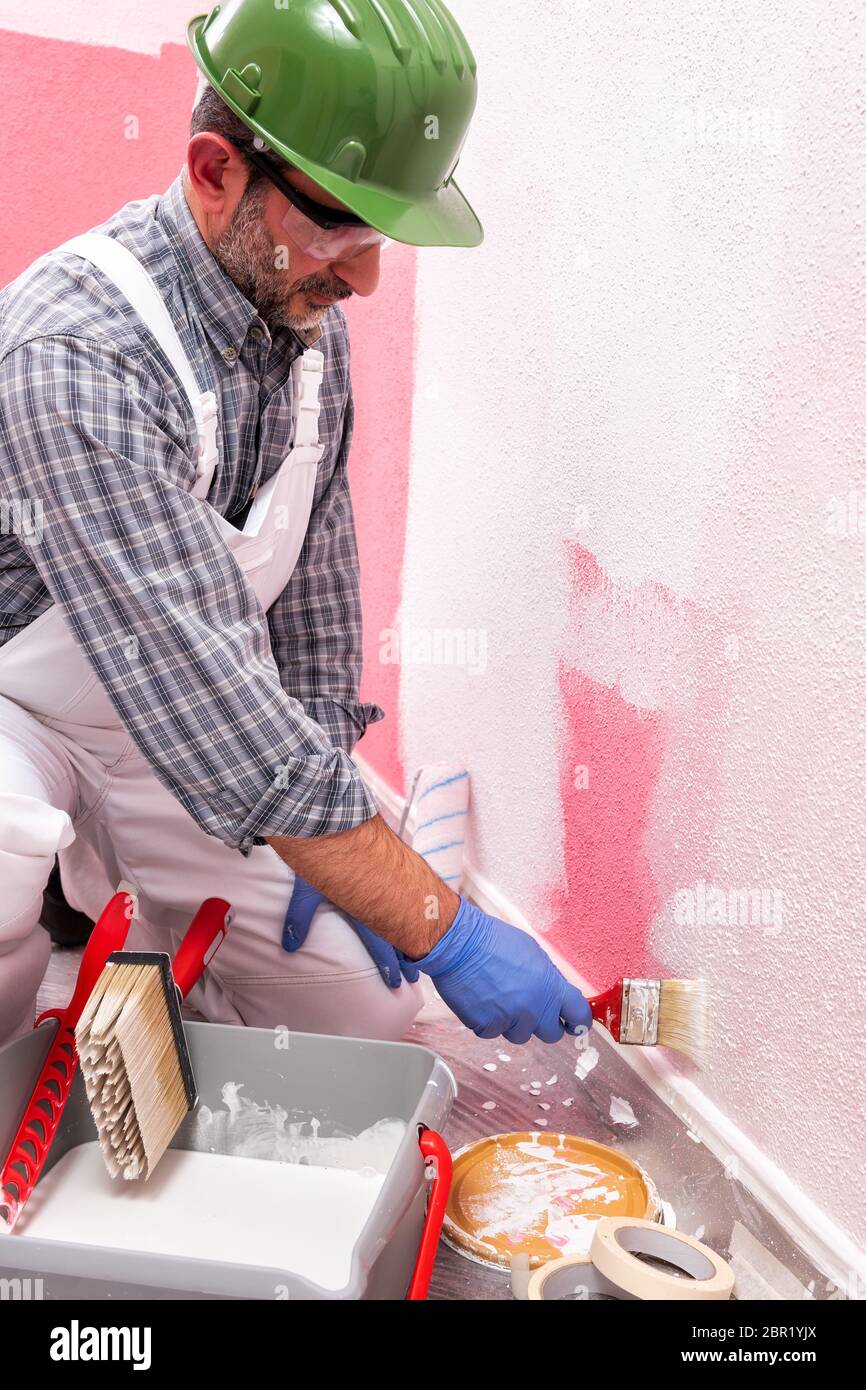 Caucasian house painter worker in white overalls, with helmet and ...