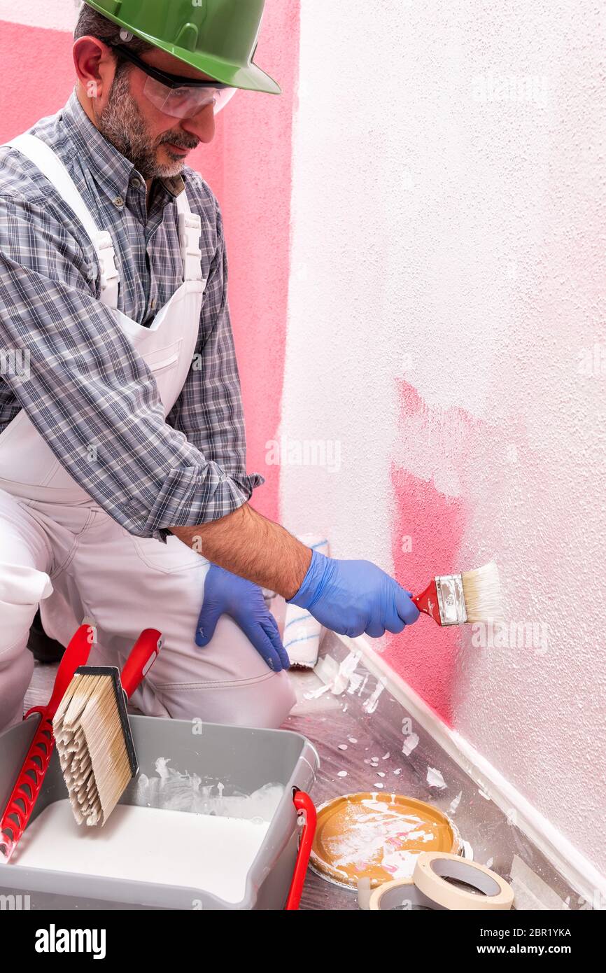 Caucasian house painter worker in white overalls, with helmet and ...
