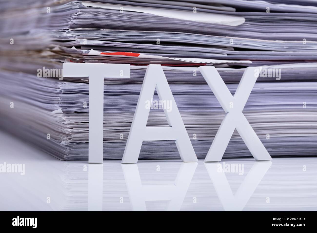 Tax Text In Front Of Stacked Paper Files On Reflective Desk Stock Photo ...