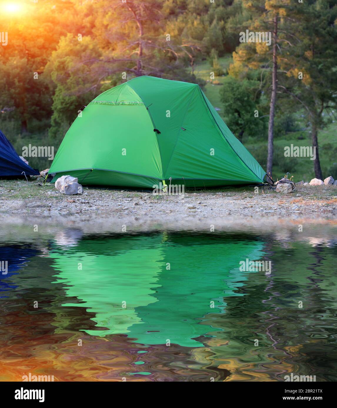 Green tourist tent on sunset background with water reflection Stock ...