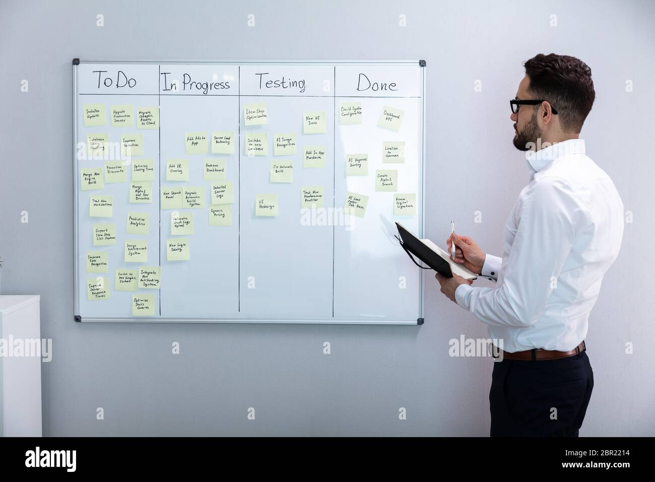 Side View Of Businessman Writing On Sticky Notes Attached To White ...