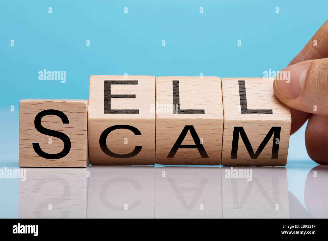 Man's Hand Holding Wooden Block With Sell And Scam Text Over Reflecting ...