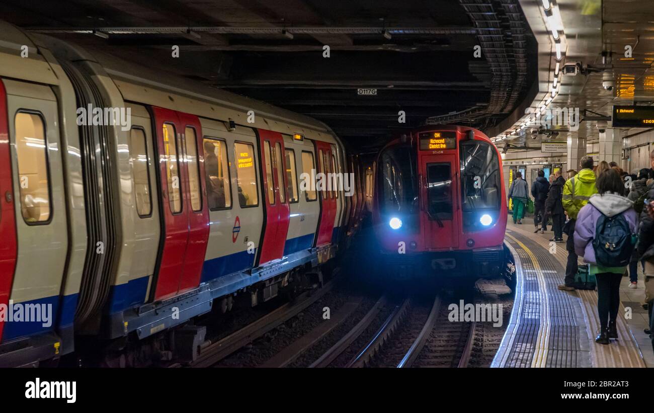 One train arrives as another leaves at a London Underground station ...