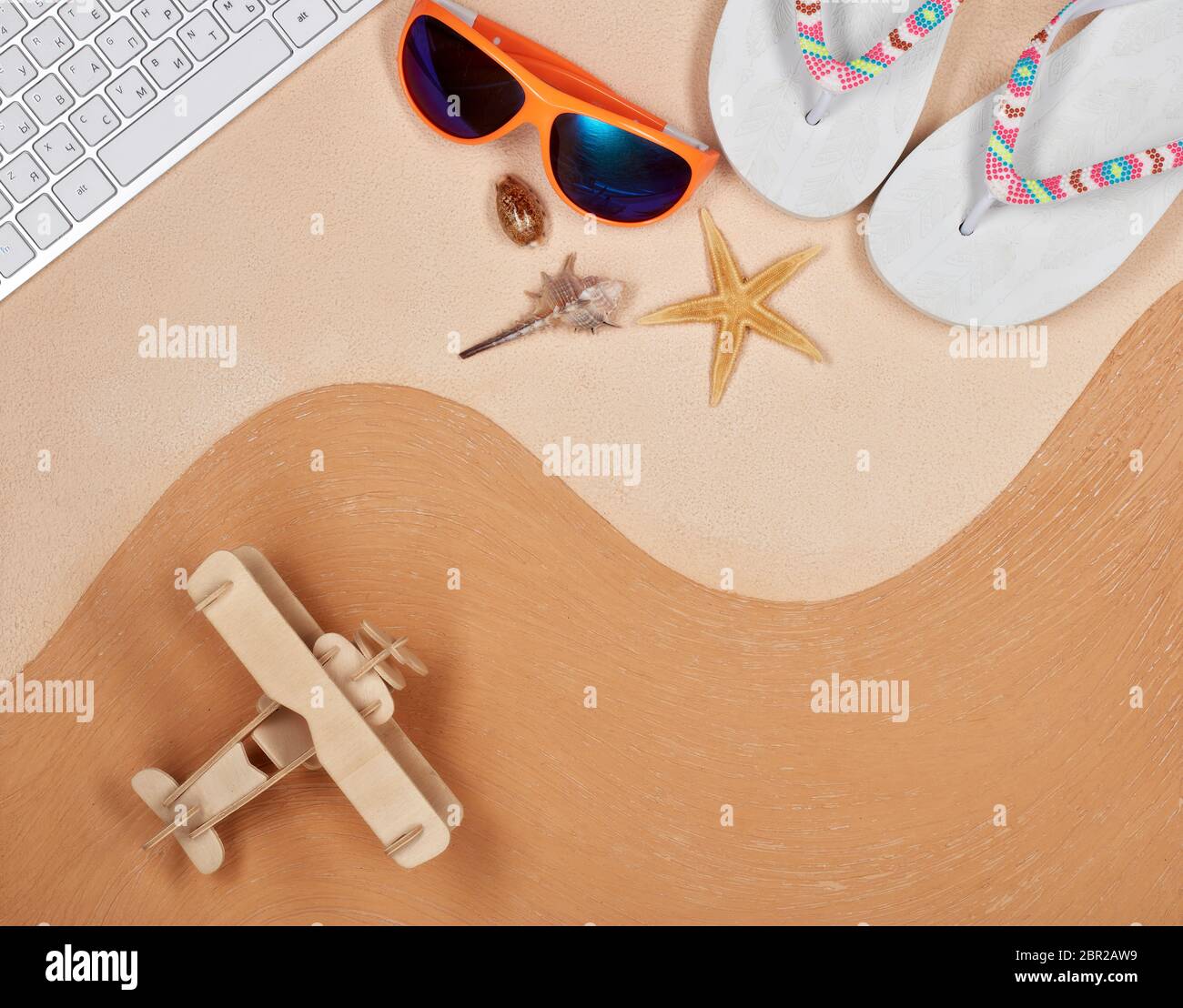 Flip flops, sunglasses, seashells, model of plane and computer keyboard ...