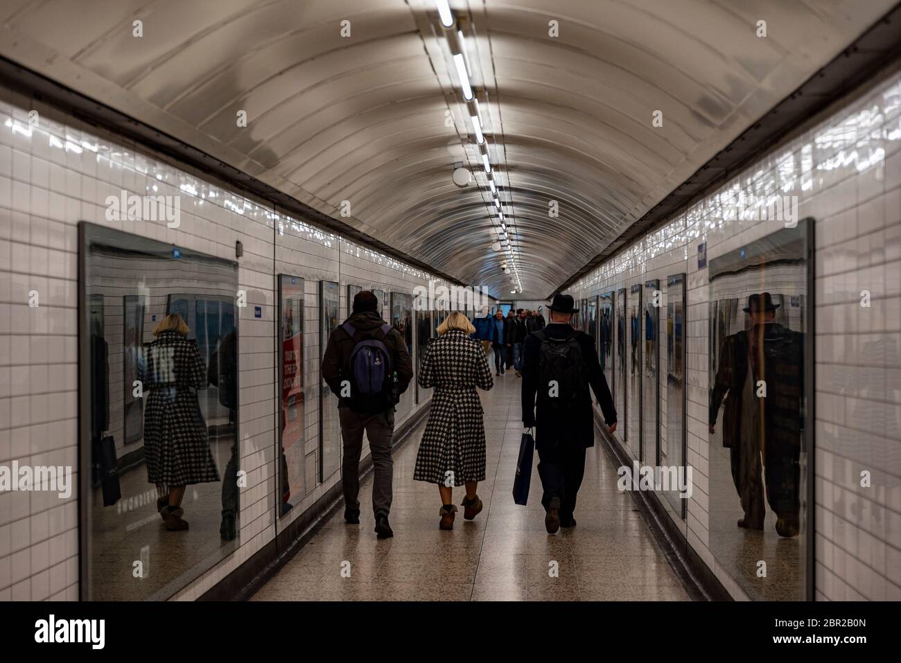 The backs of three people as they walk through a London underground ...
