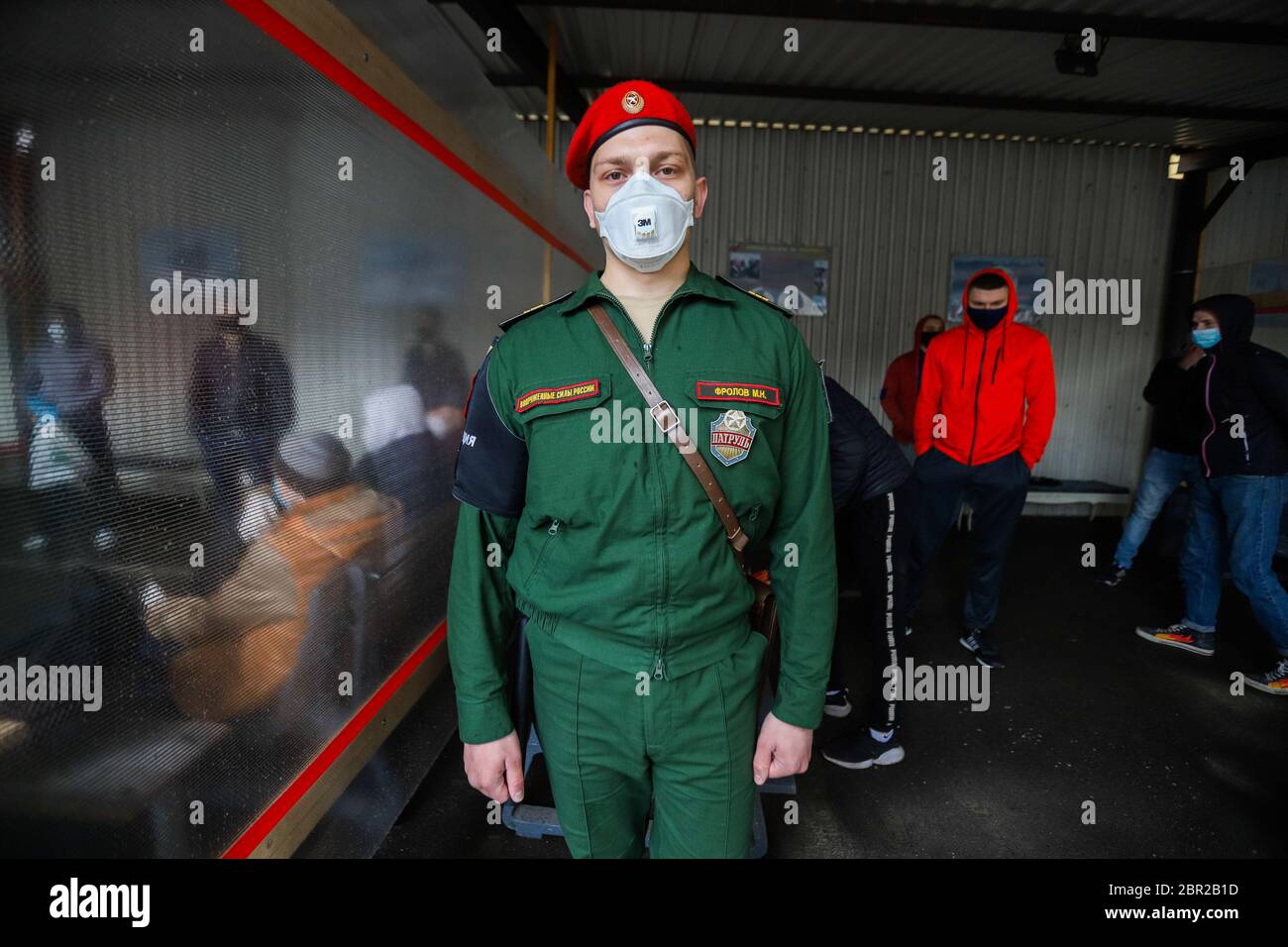 A Russian military policeman wearing a face mask guards recruits at the ...