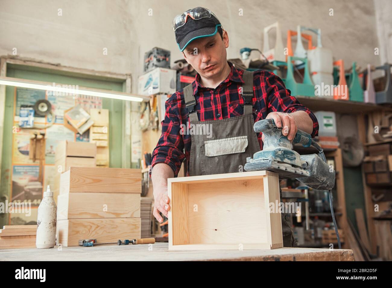 Worker grinds the wood box of angular grinding machine Stock Photo - Alamy