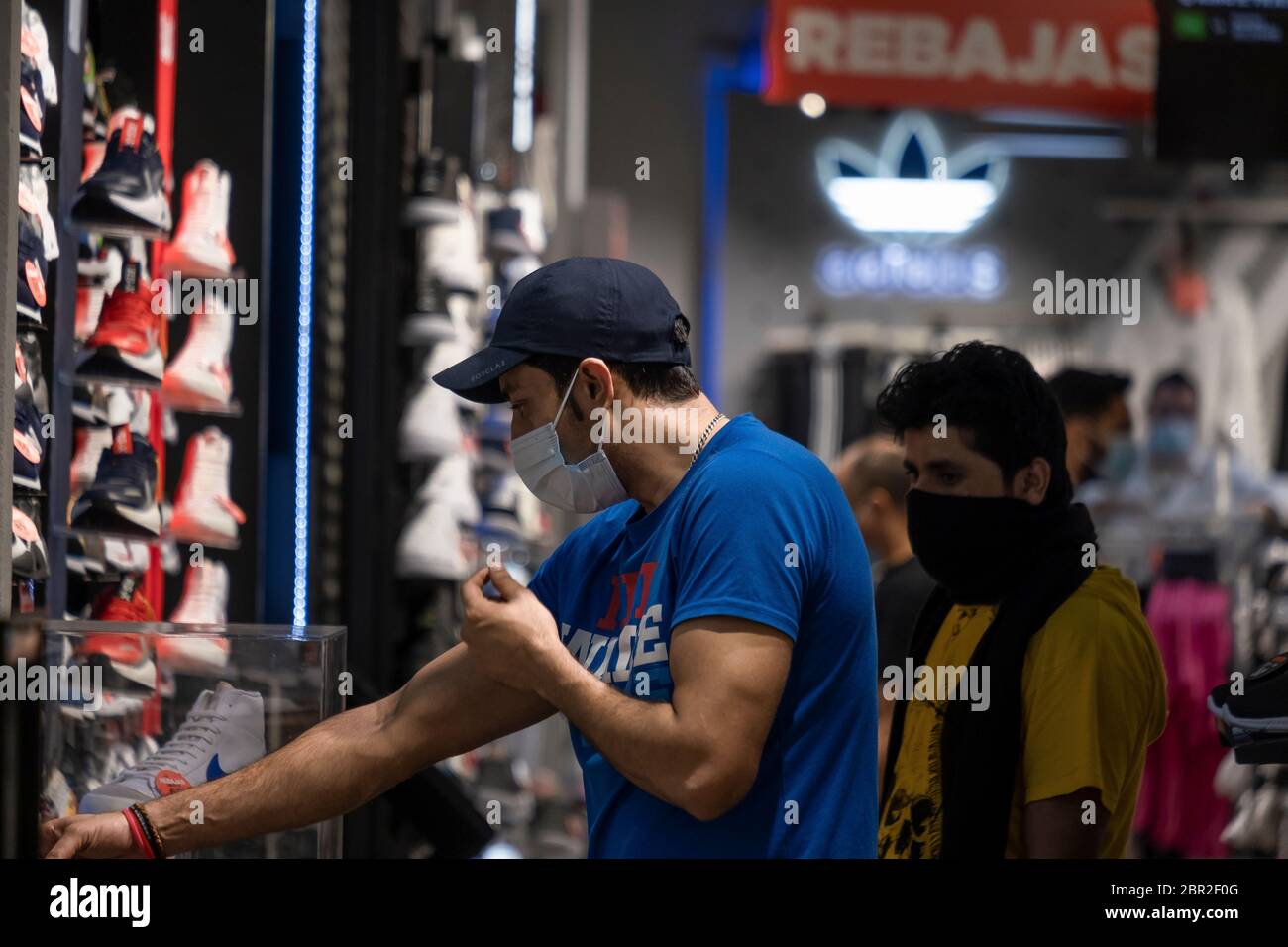 A customer wearing a face mask as a preventive measure looks at models ...